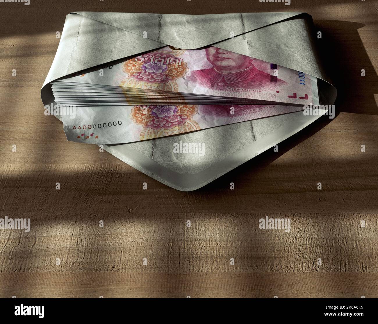 A spreading pile of chinese yuan banknotes in an envelope on a wooden ...