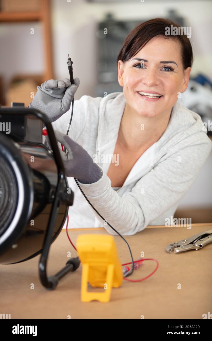 happy female electrician measures the voltage of a device Stock Photo ...