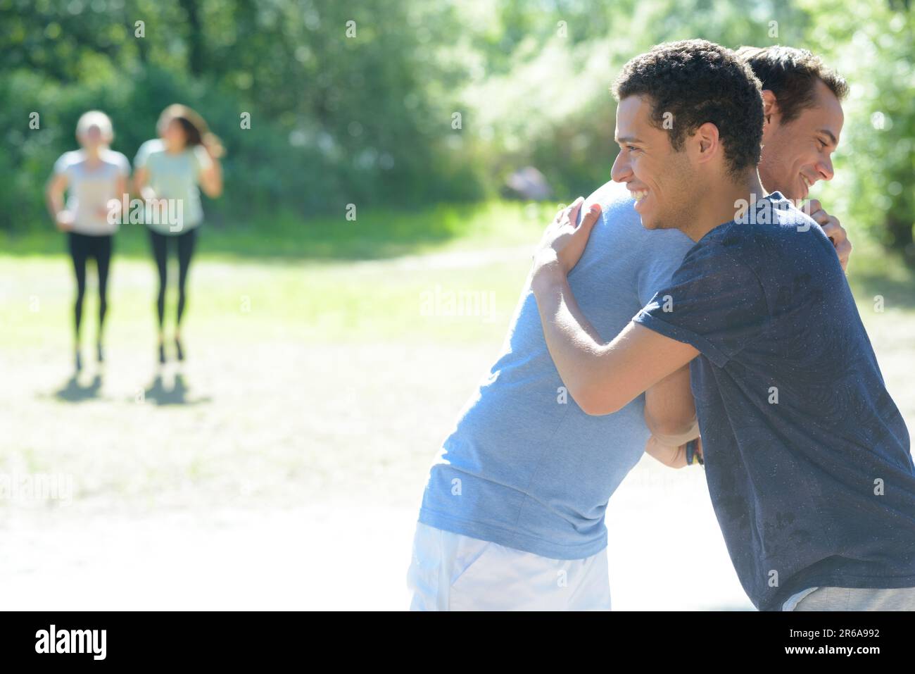 two young sportmen giving eachother a hug Stock Photo - Alamy