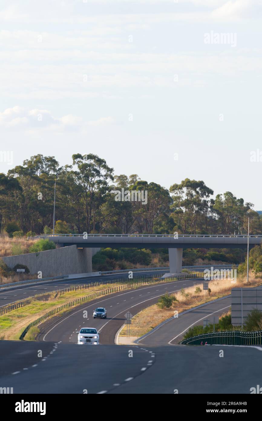 Cars on highway showing asphalt motorway, bush and tree background, and ...