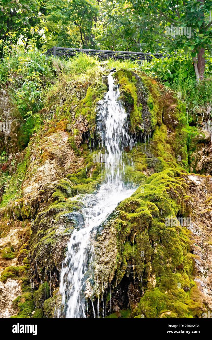 Source water flowing from a low cliff against the background of stone ...