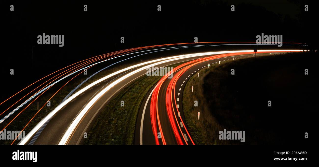 An aerial long-exposure view of car light trails on a highway road at ...
