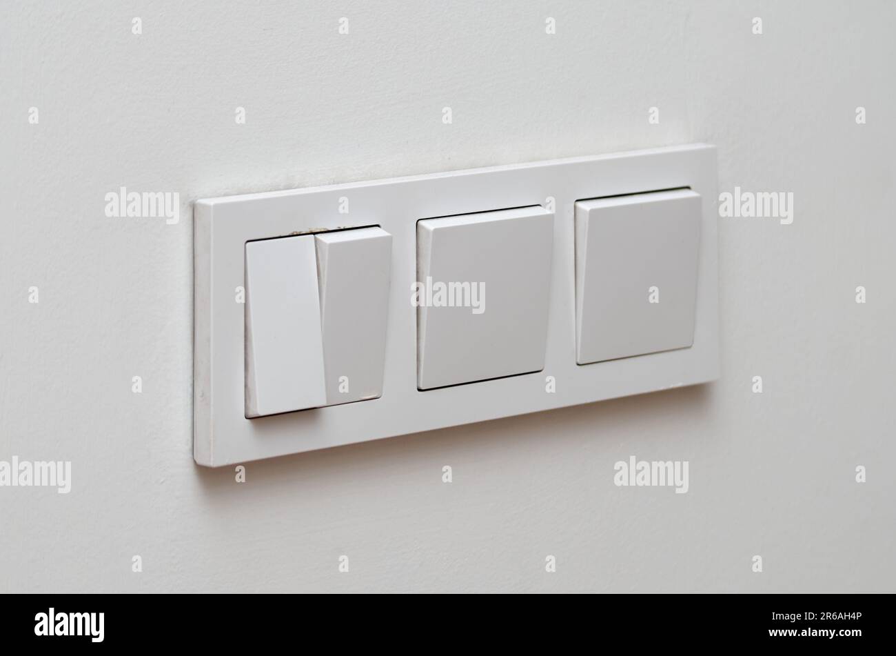 Block of three white plastic electrical switches on a white wall Stock ...