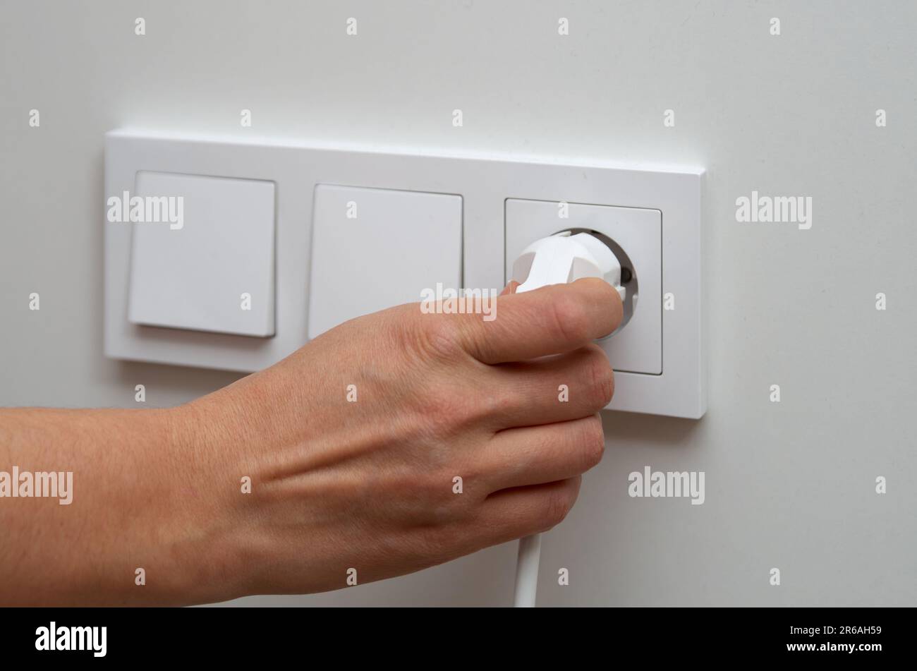 Woman's hand plugs an electric plug into a socket Stock Photo - Alamy