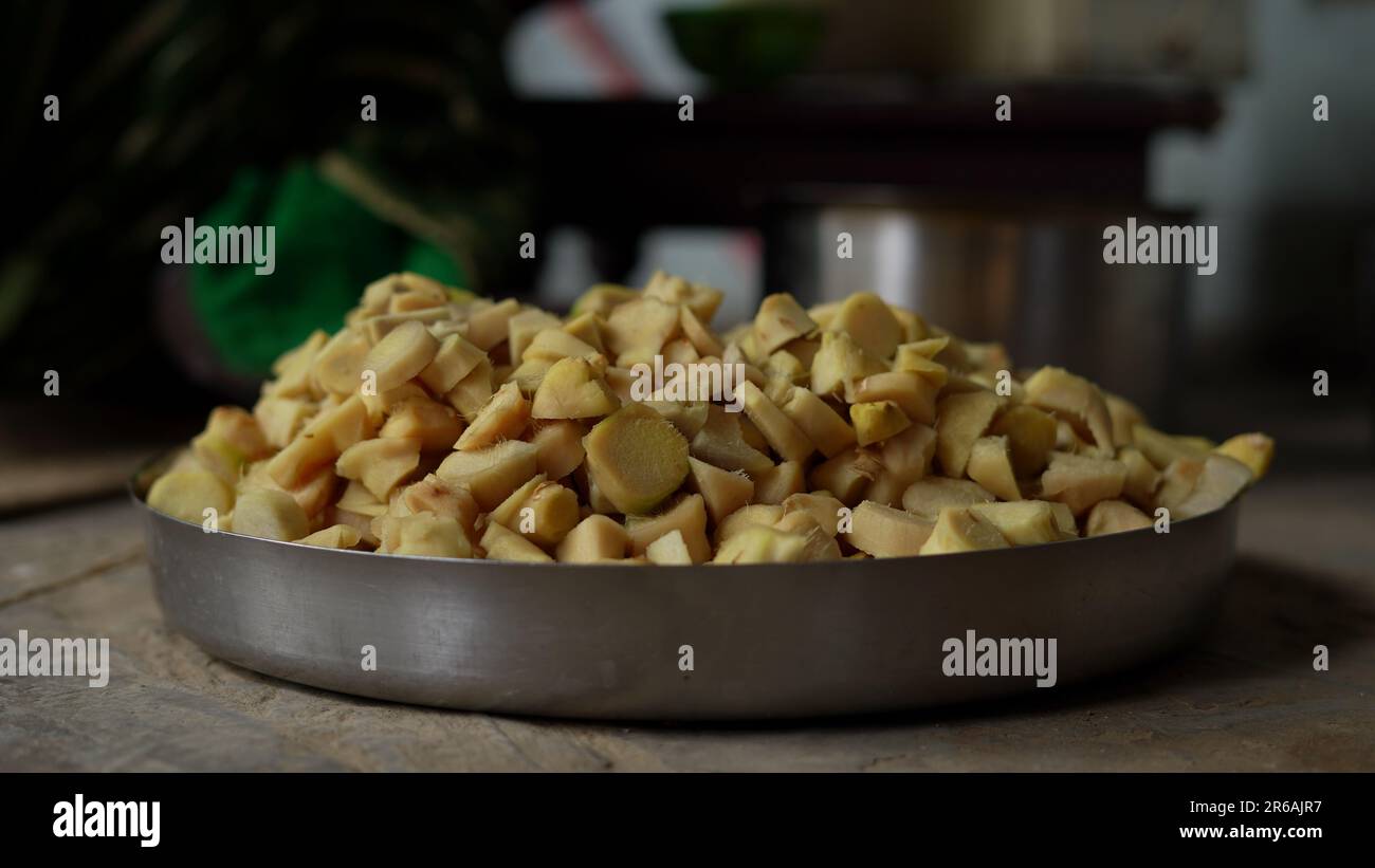 Fresh ginger roots, whole and sliced, in a stainless steel bowl ...