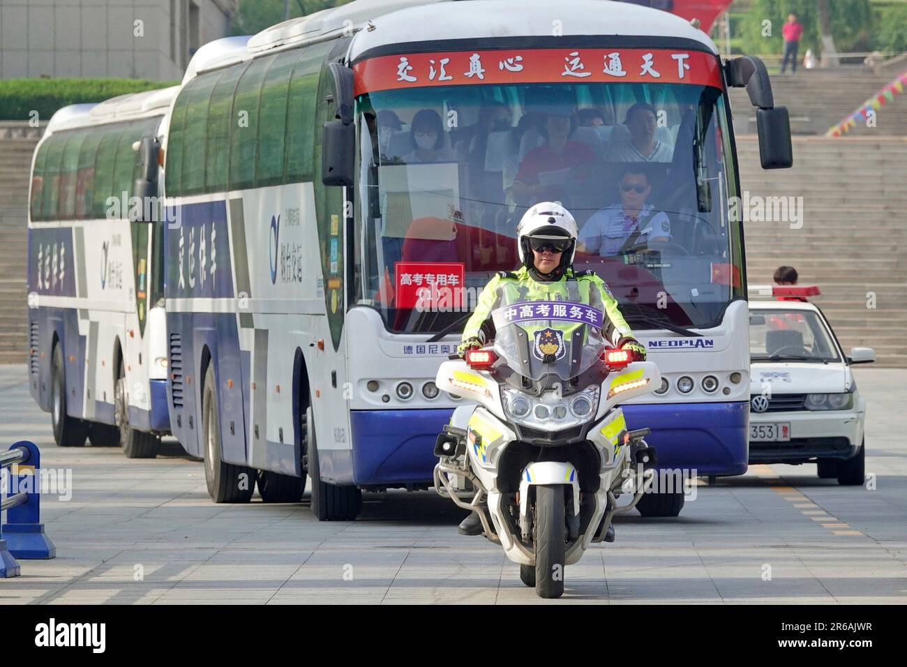 A policeman leads a fleet of buses carring the Gao Kao examinees to an ...