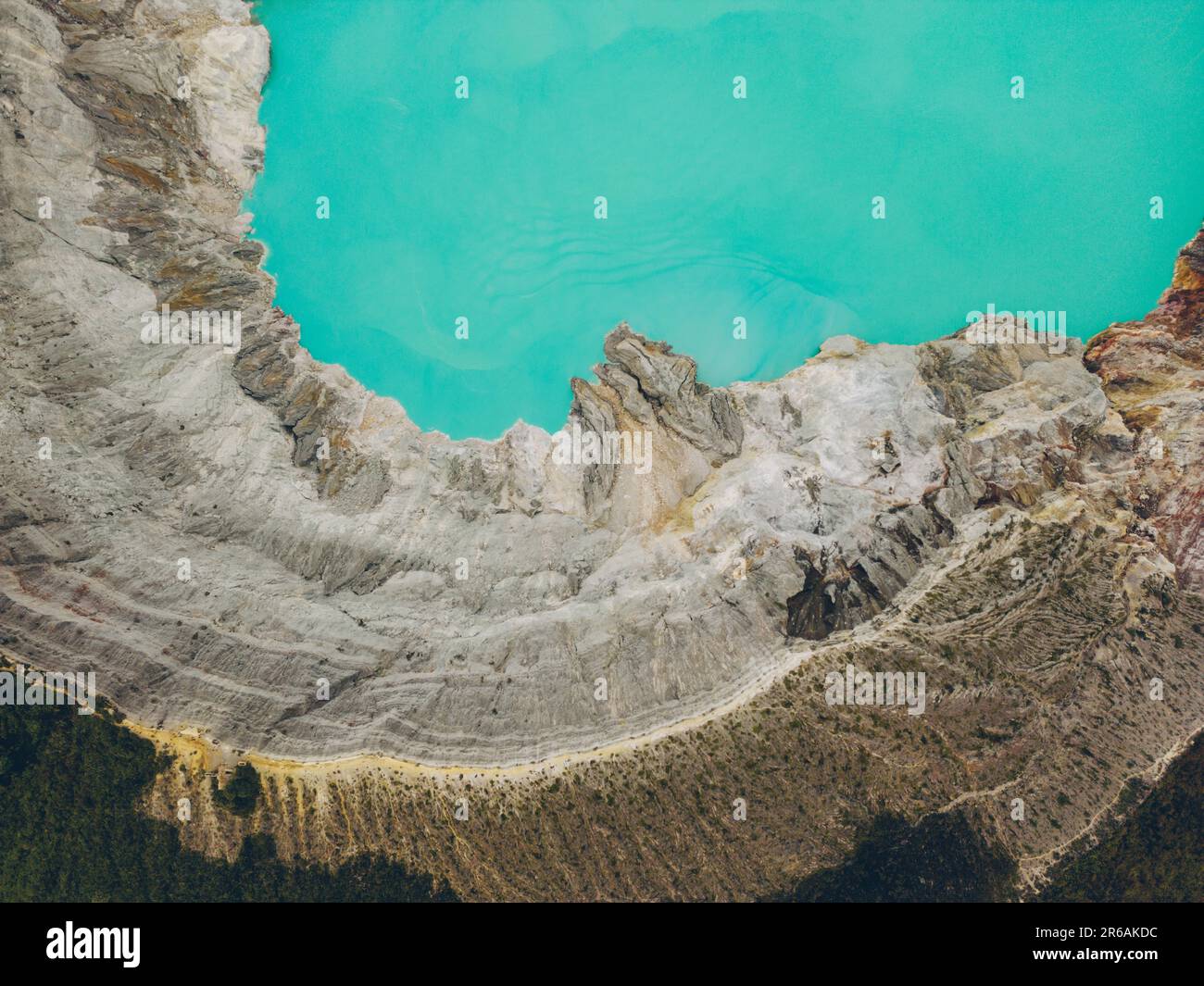 Top aerial view of turquoise sulfur water lake, surrounded by rock cliff at Kawah Ijen volcano ...