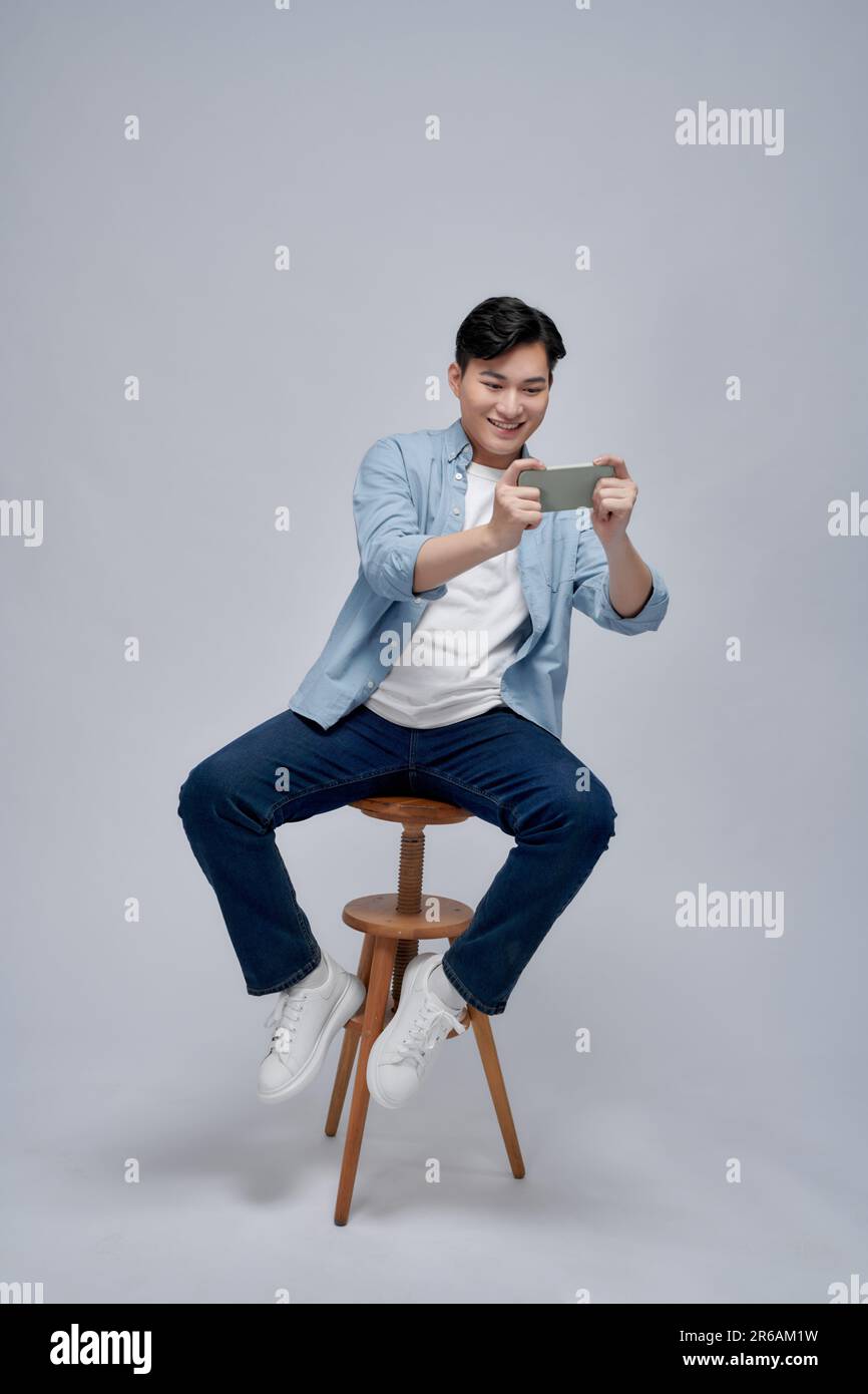 Full body profile side photo of young man sit on a stool play game ...