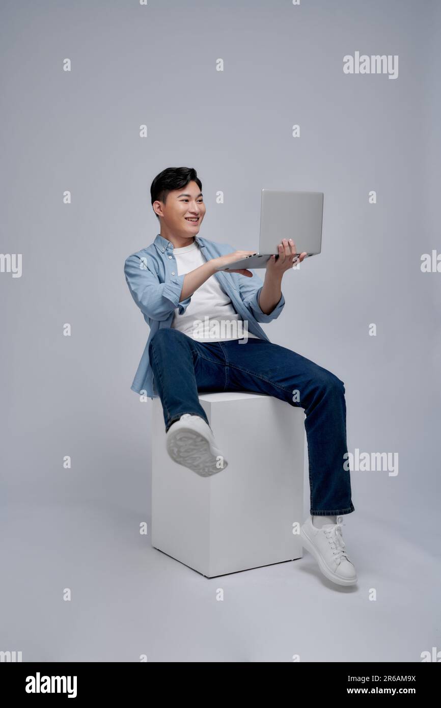 The young adult Asian man sitting the platform on the white background ...
