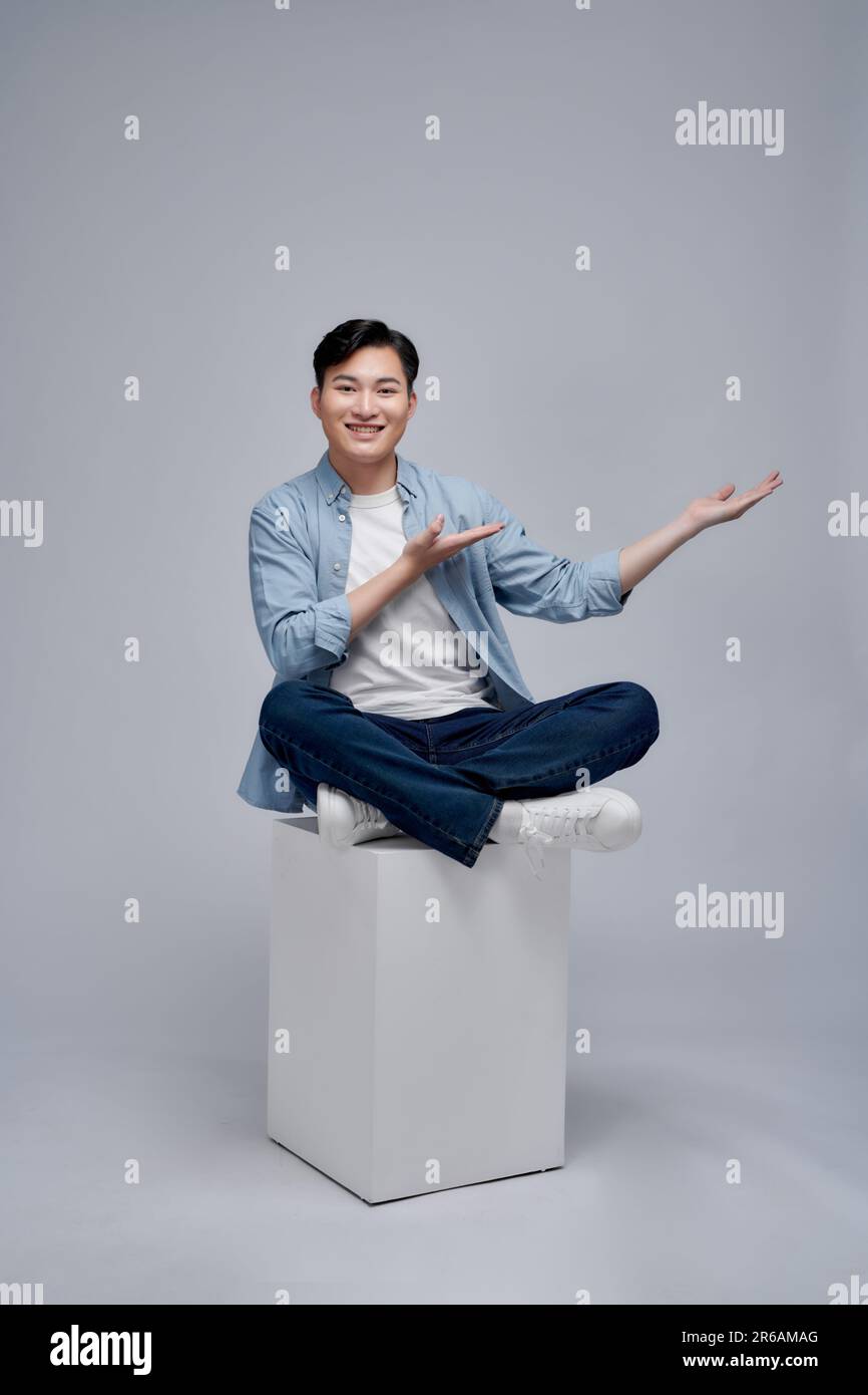 portrait of handsome young man model sitting cube posing in studio ...