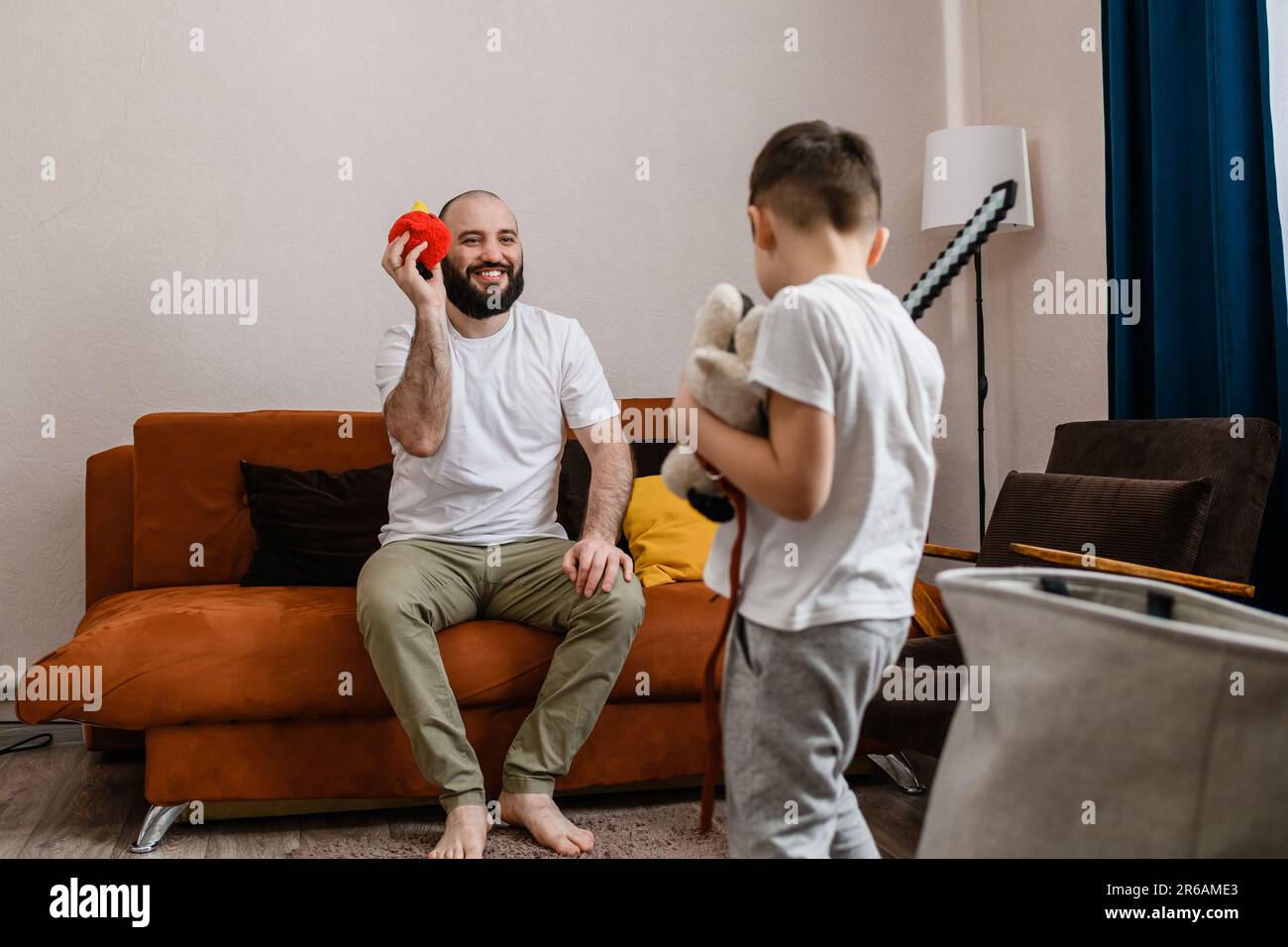 Father and son play with soft toys at cozy home living room sofa, child ...