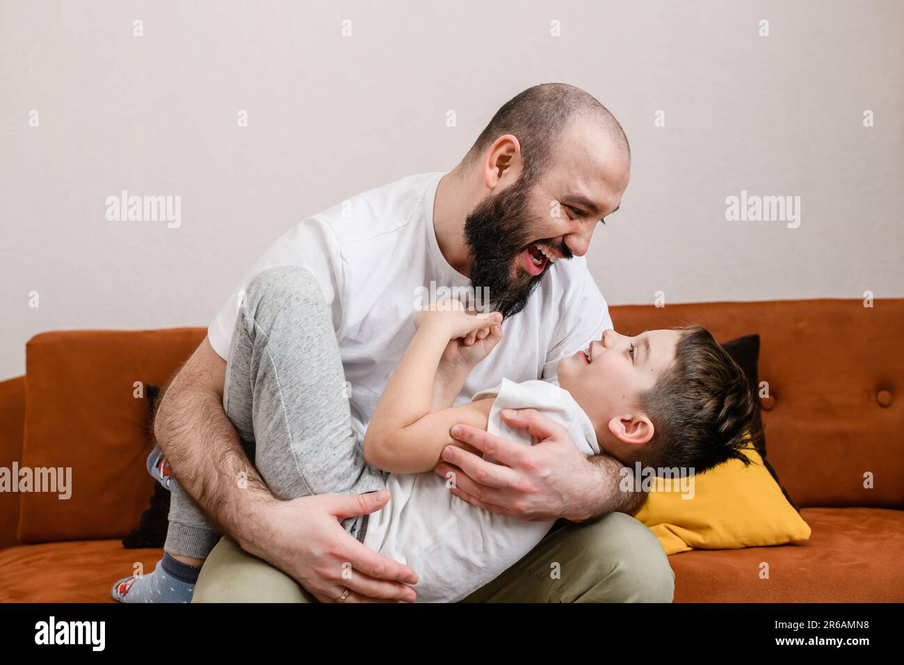 Father hug little baby boy at home sofa with emotional face, daddy love ...