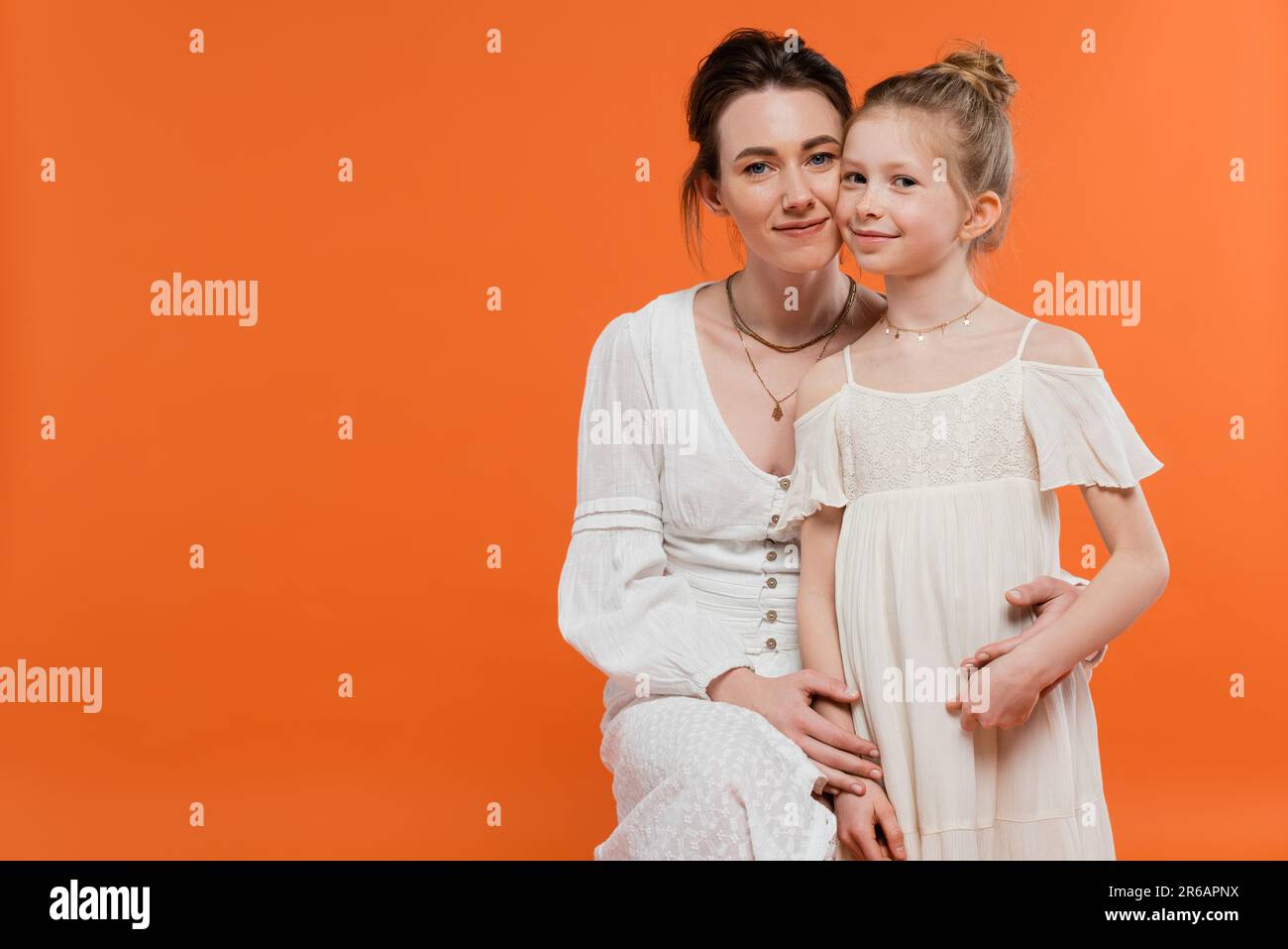 motherly love, happy young woman hugging preteen girl on orange ...