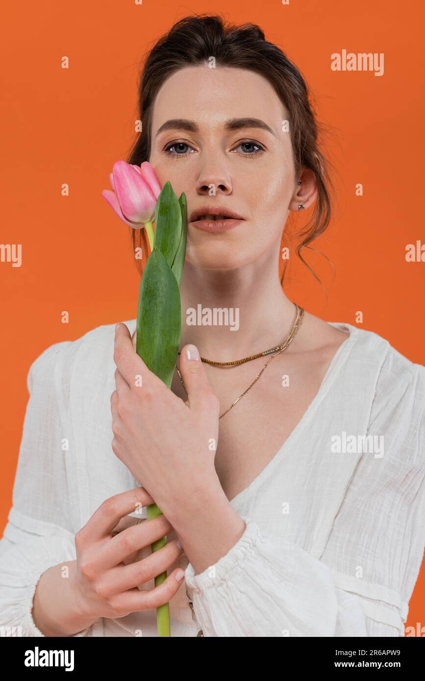 everyday fashion, young woman in white sun dress holding pink tulip and ...