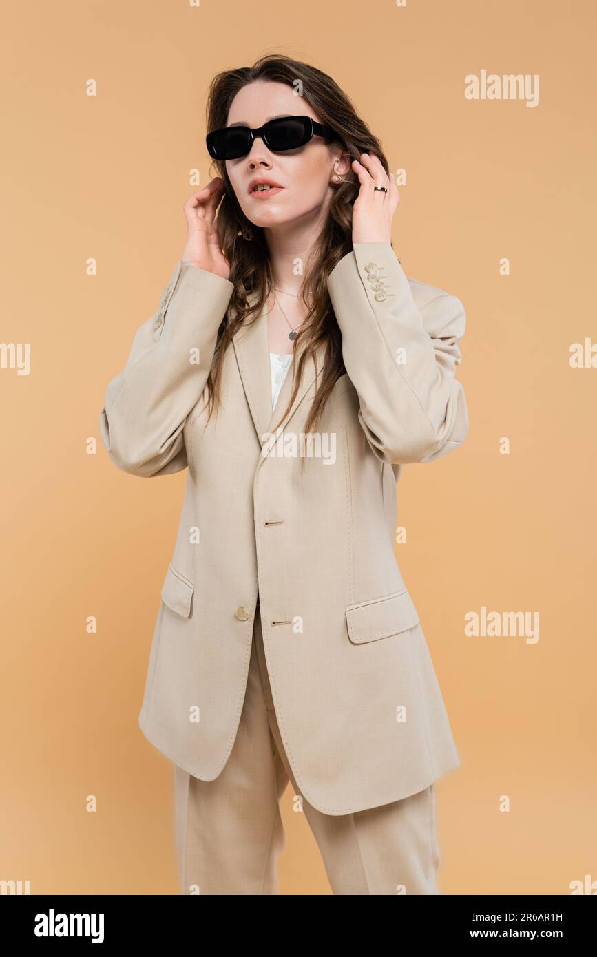 fashion trend concept, young woman adjusting wavy hair and standing in ...