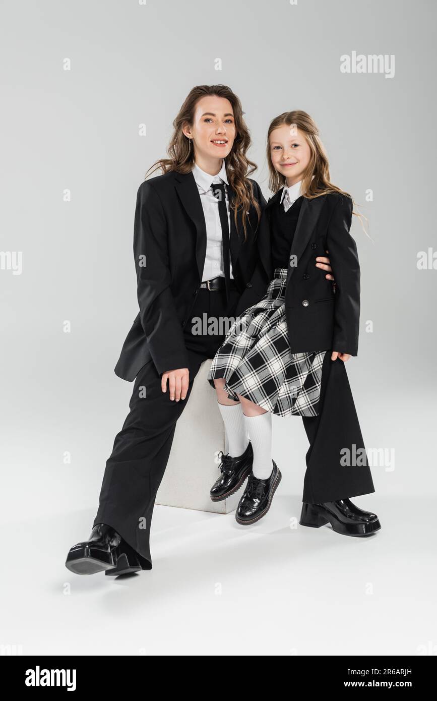 working mother and daughter, happy businesswoman and schoolgirl sitting ...