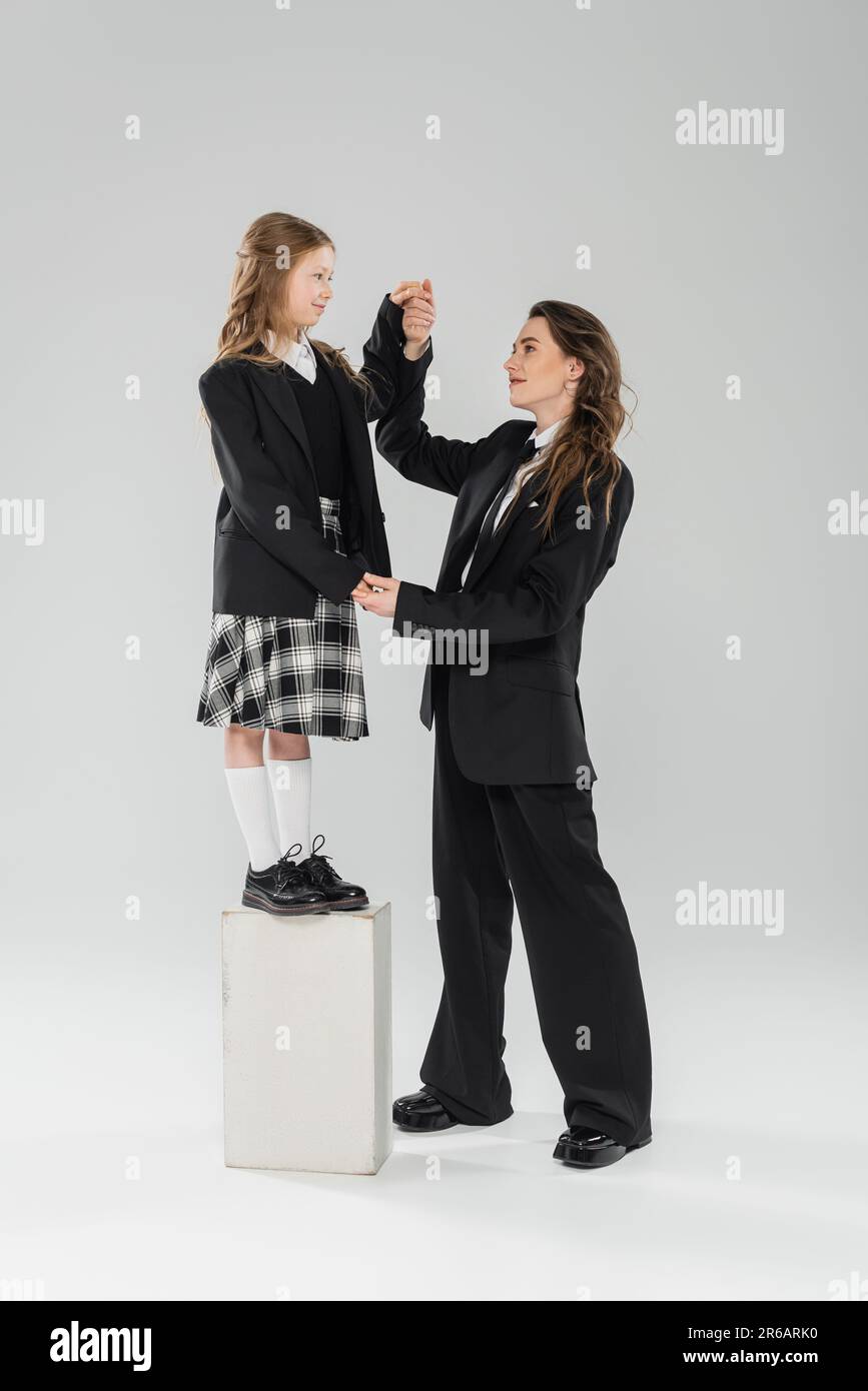 mother and schoolgirl, happy girl standing on concrete stool near ...