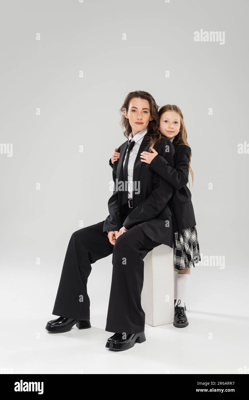 happy girl hugging mother, businesswoman sitting on concrete stool near ...