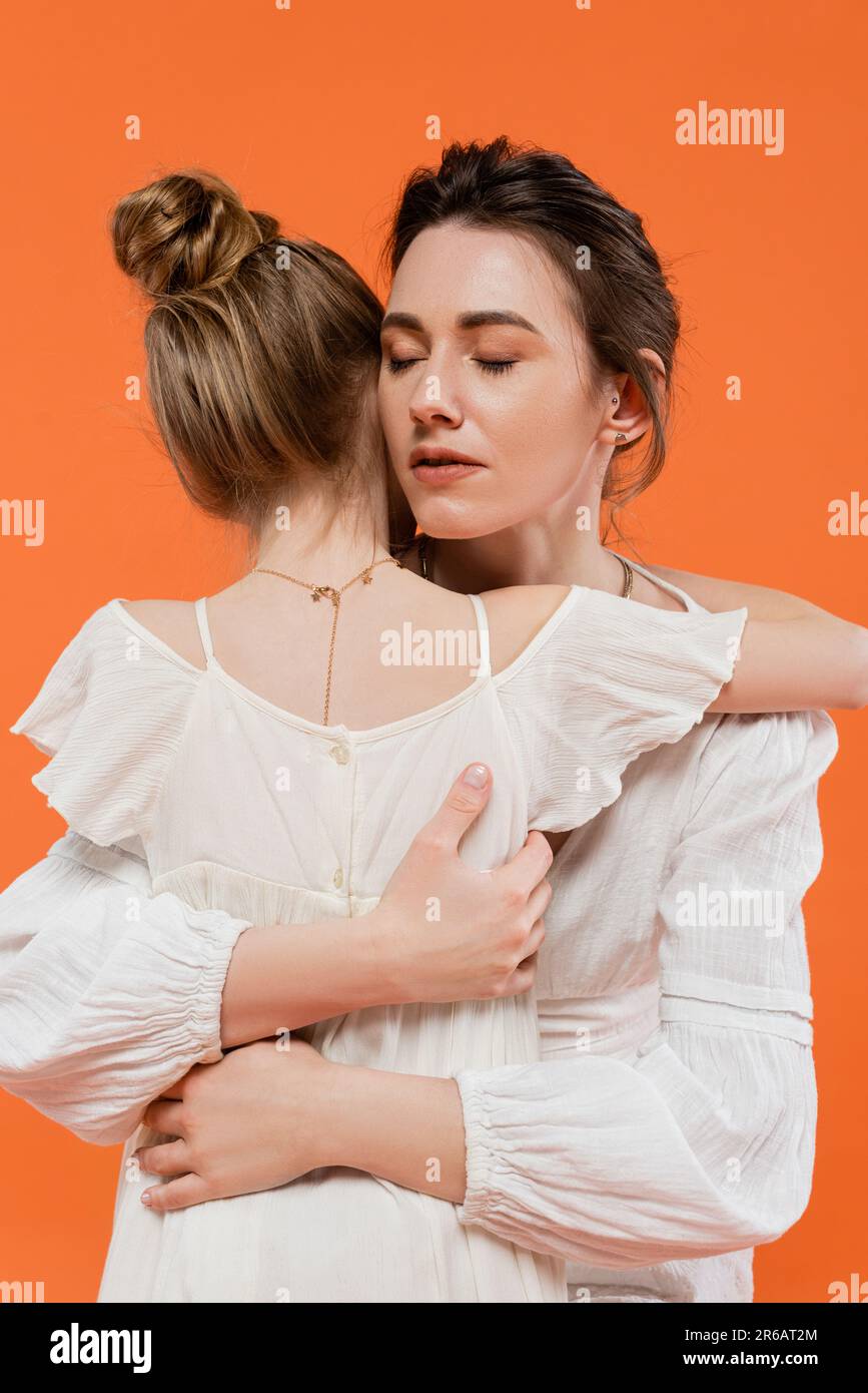 motherly love, caring mother hugging daughter on orange background ...