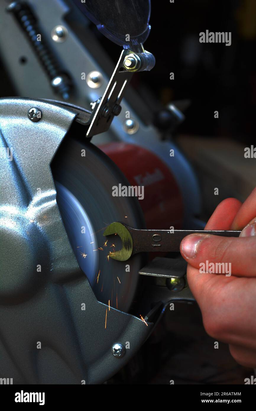 A person is focused on their task as they use a grinding wheel to work ...