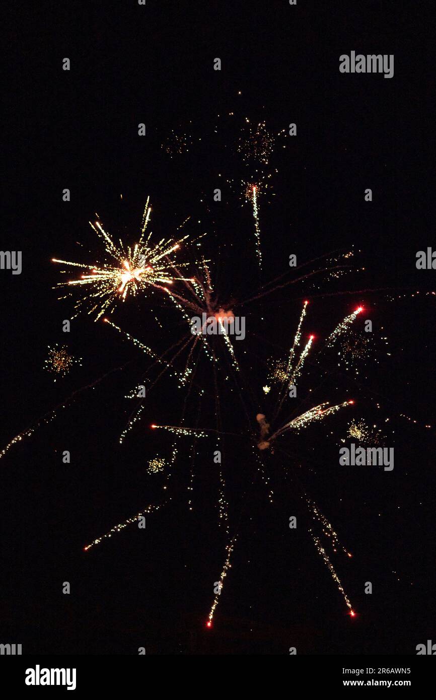 Small fireworks at night against black night sky with half moon, during ...