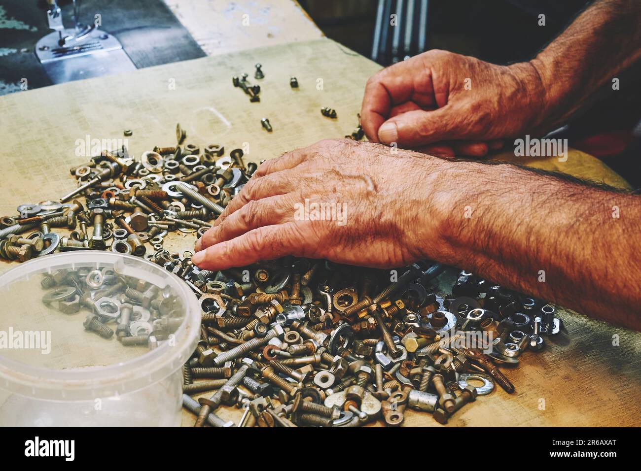 Hands of a craftsman mechanic choose the right bolt nut for repair ...