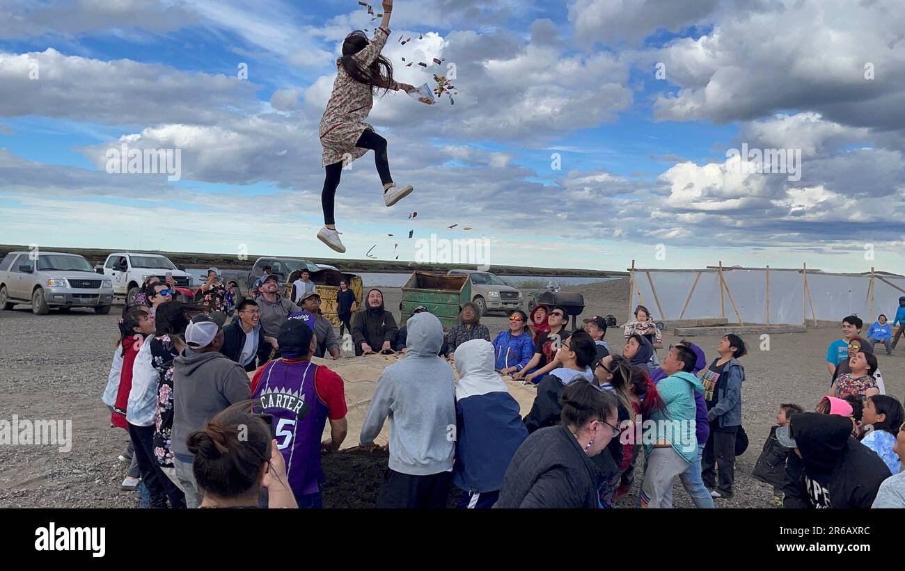 A group of people holding a trampoline for a person jumping on it Stock ...