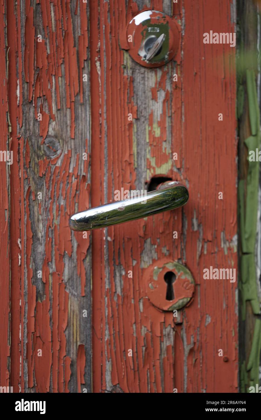 A close-up image of a rusty old door handle, with the latch open and ...