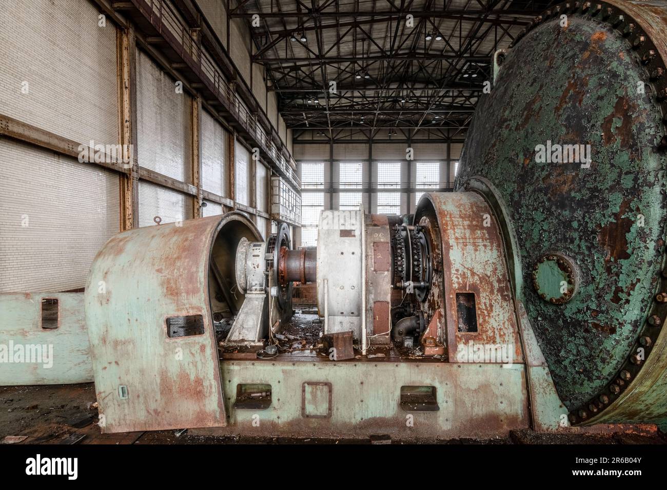 A vintage industrial machine is displayed in an empty factory space ...