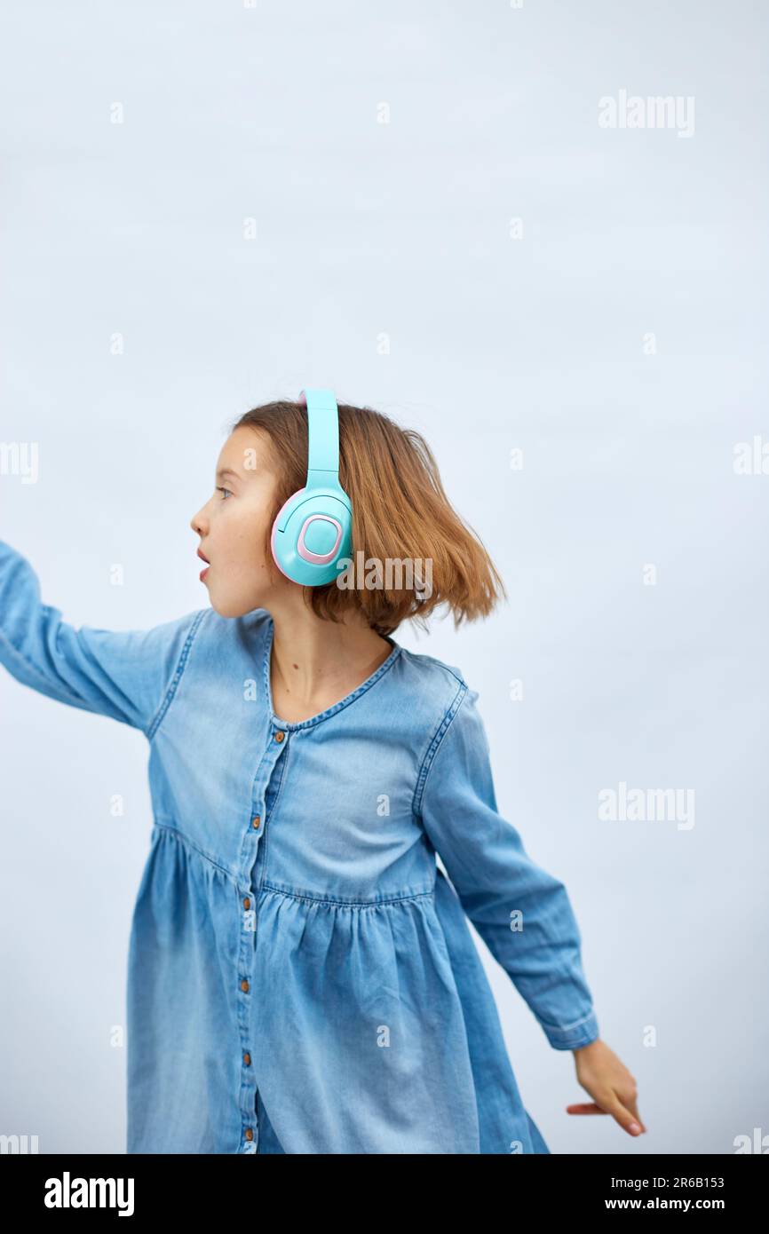 Girl teenager in casual denim dress listening to music in headphones on ...