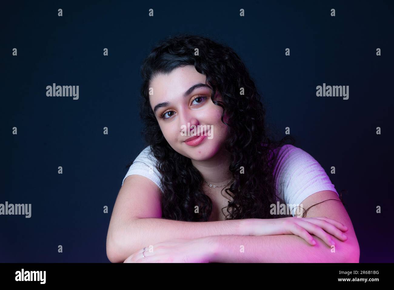 A cheerful woman with curly hair is beaming and making direct eye ...