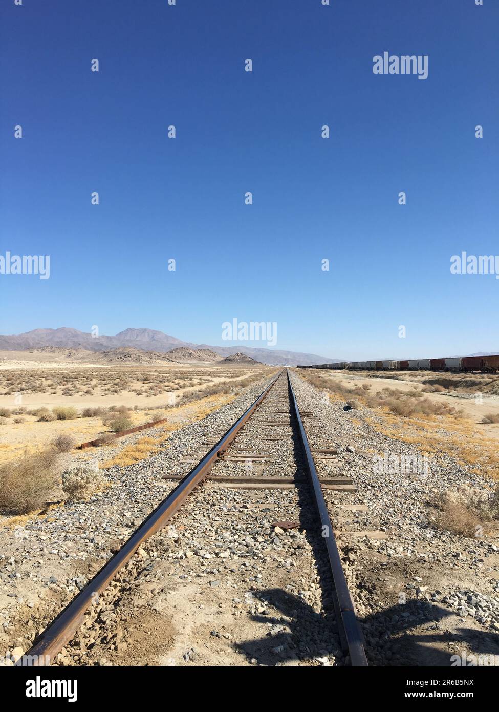A vertical shot of a train track stretching through a desert landscape ...