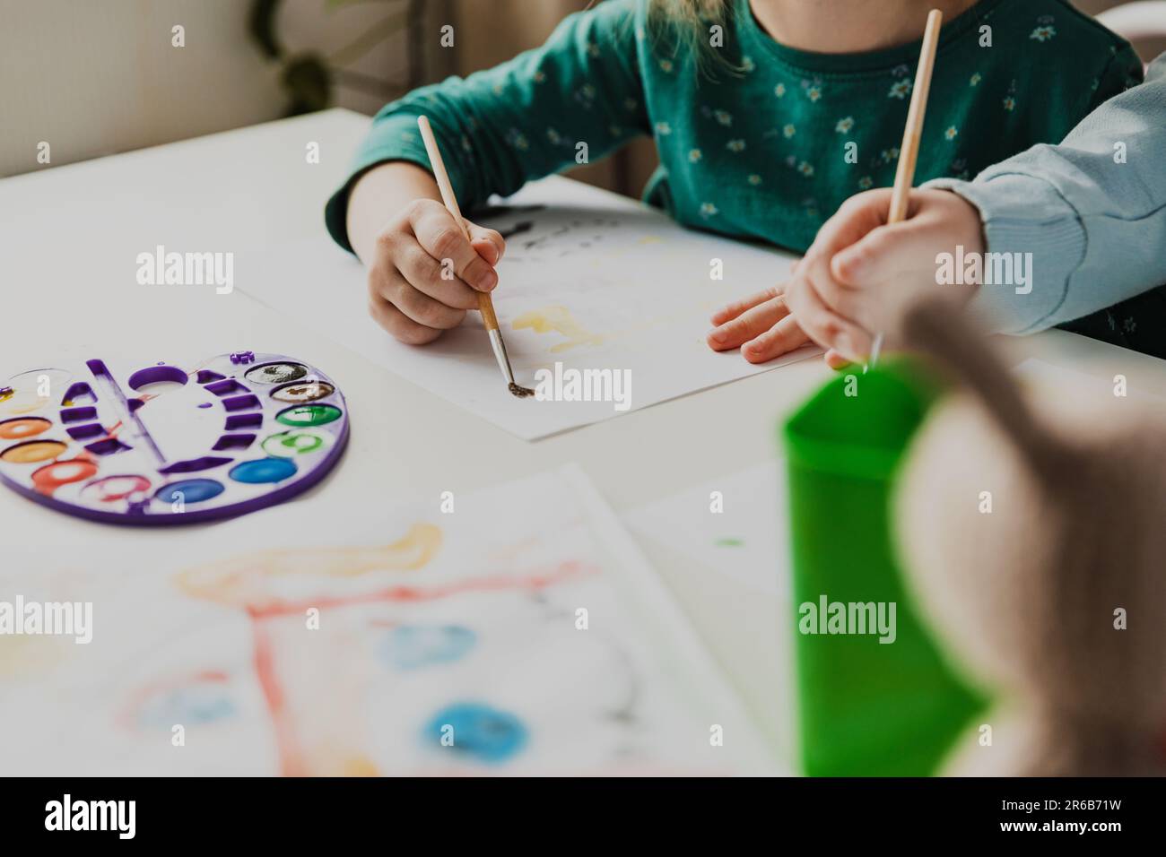 Two cute little sisters, classmates are painting on table. Small ...