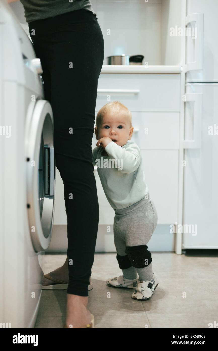 Little infant baby boy child hiding between mothers legs demanding her ...