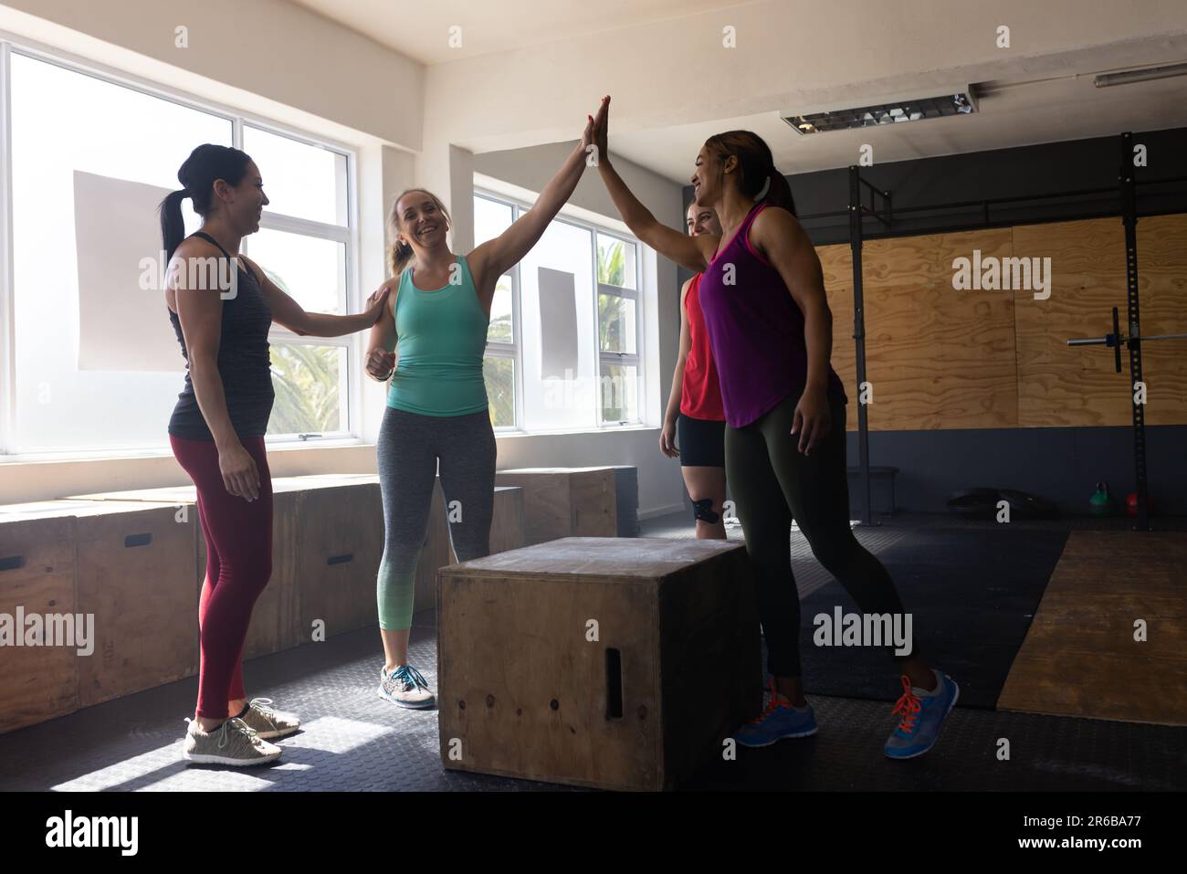Cheerful multiracial female friends giving high-five while standing by ...