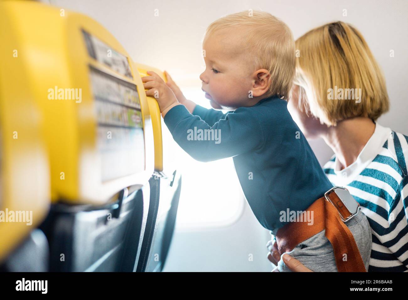 Mother and infant baby boy child flying on comercial flight, traveling ...