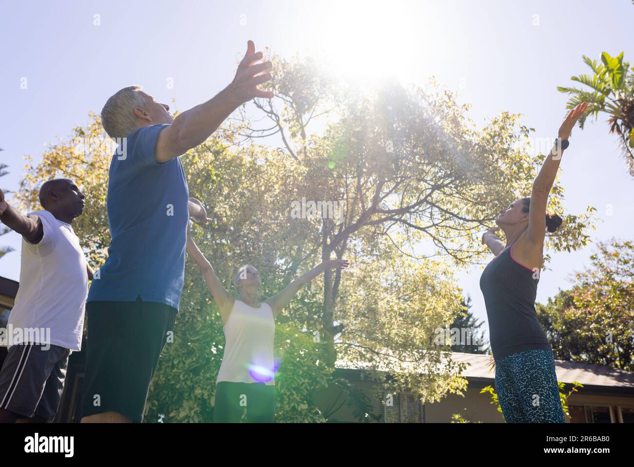 Focused diverse seniors exercising with female pilates coach in sunny ...