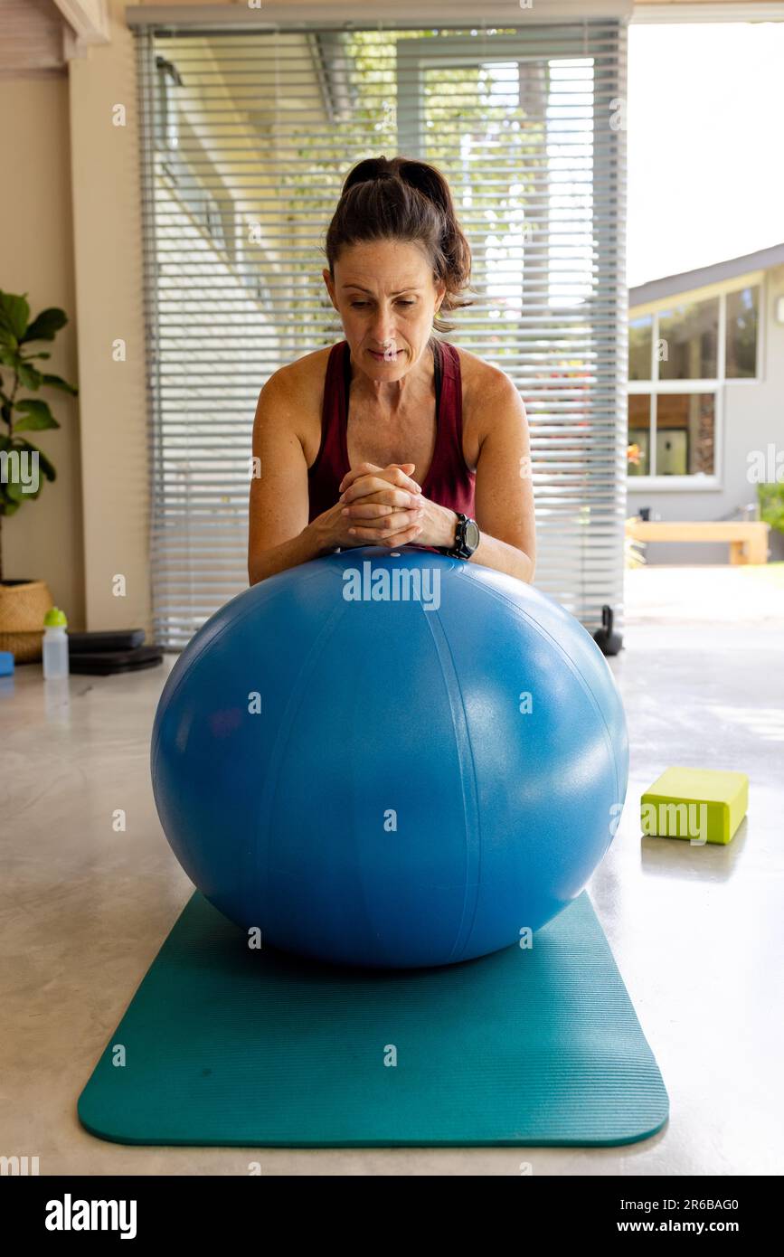 Focused caucasian female coach using exercise ball in pilates class ...