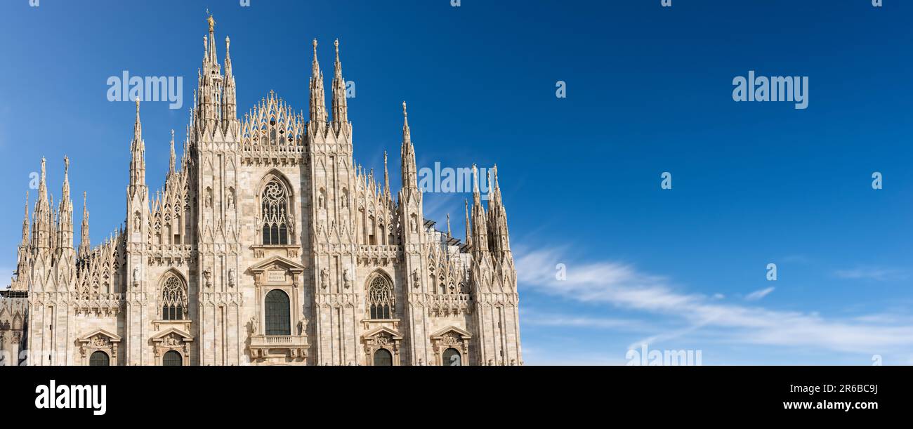 Facade of the Duomo di Milano against a clear blue sky with clouds and ...