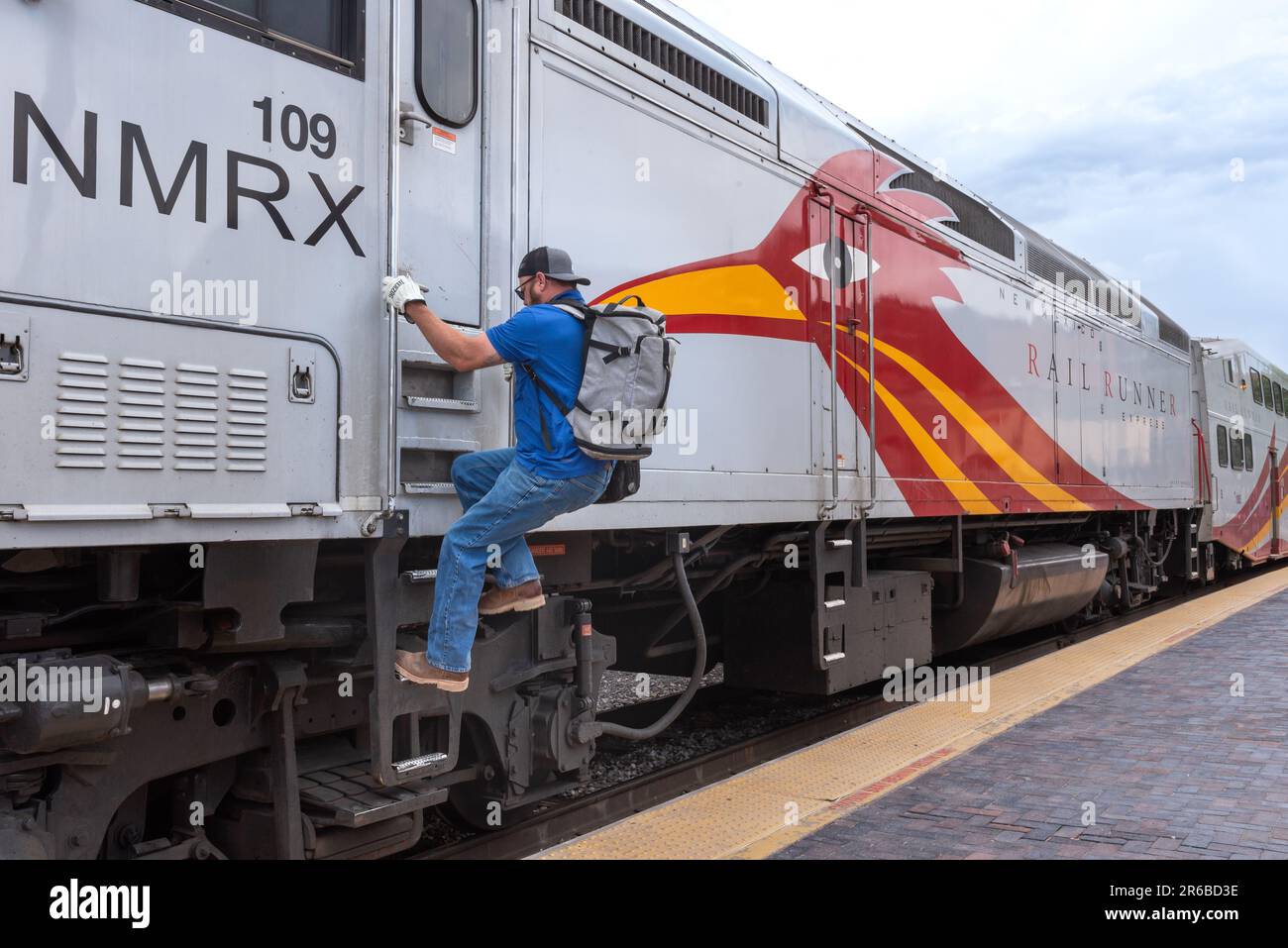 A male worker climbs onboard the engine for the Rail Runner, a commuter ...