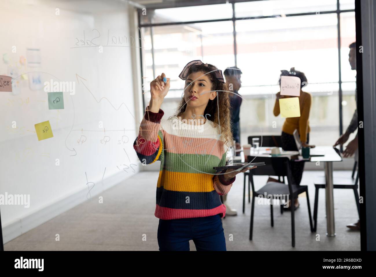Busy diverse business people taking notes on glass wall and discussing ...