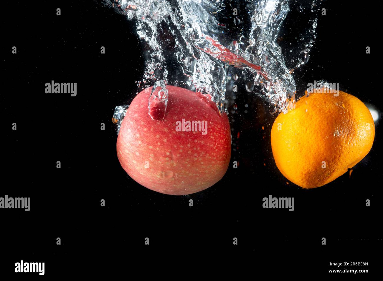 High speed flash image of an apple and an orange fruit falling into the ...