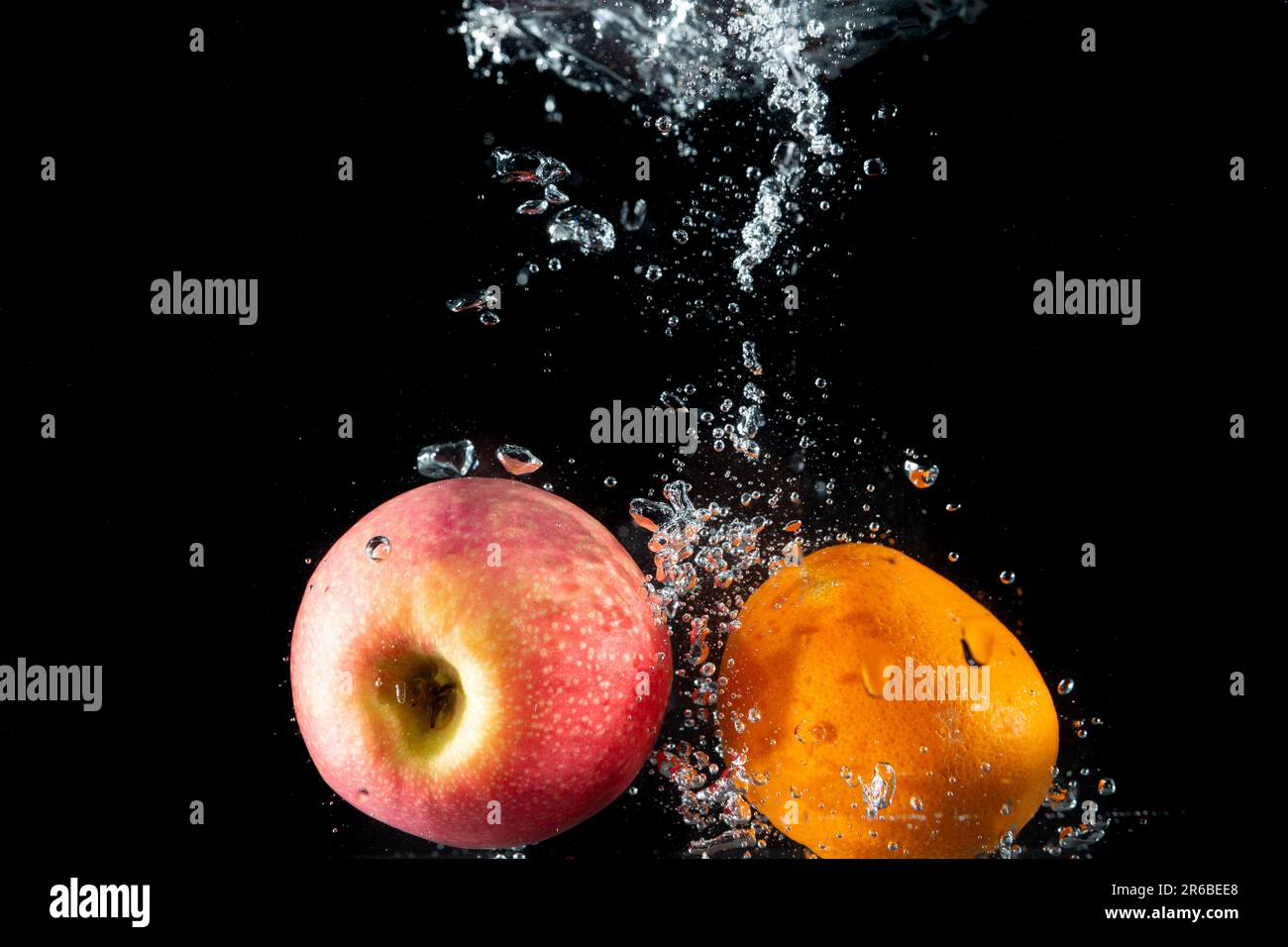 High speed flash image of an apple and an orange fruit falling into the ...