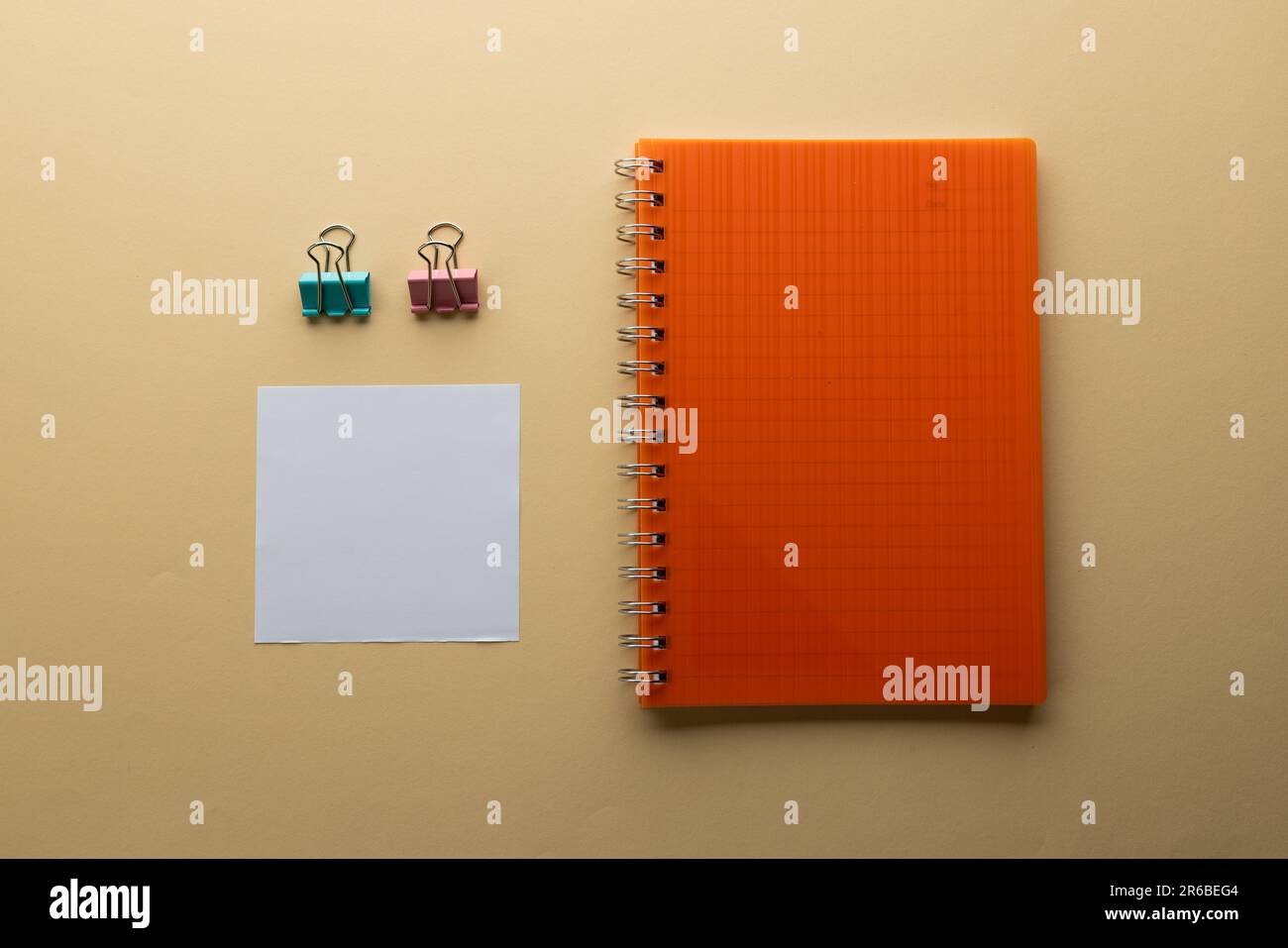 Flat lay of orange notebook, memo note and paper clips with copy space ...