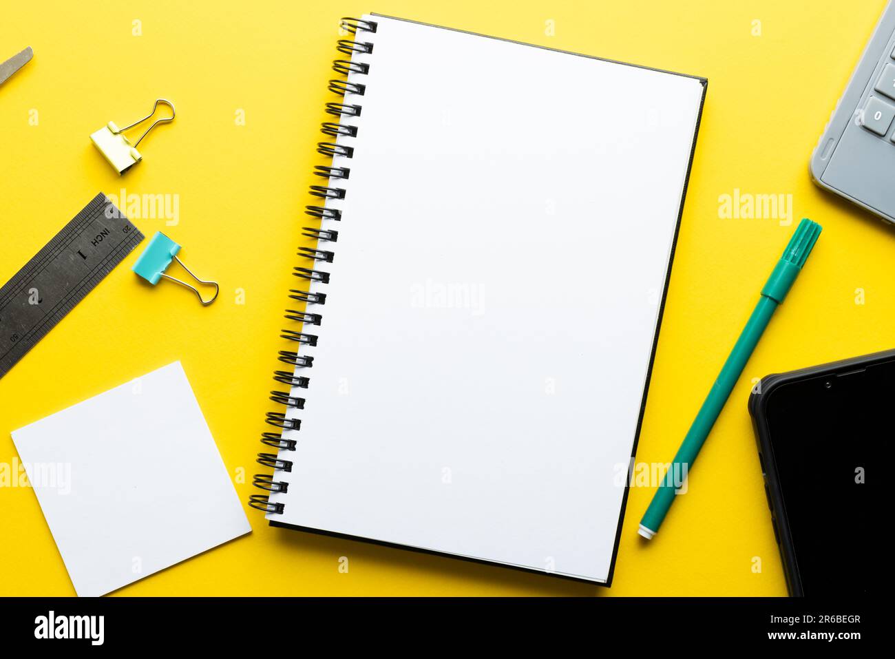 Flat lay of notebook with copy space and writing materials on yellow ...