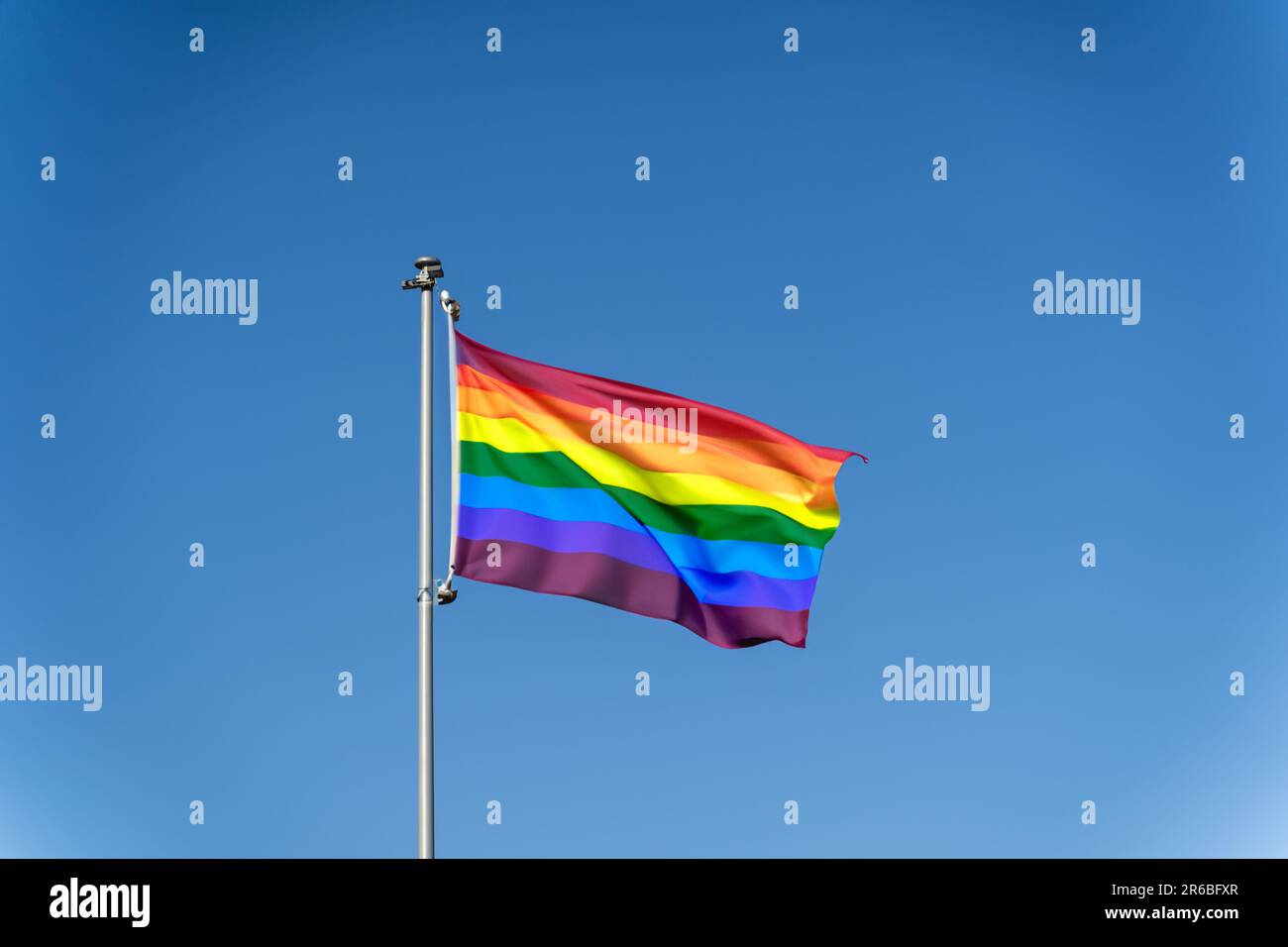 LGBTQ rainbow flag waving against a clear blue sky Stock Photo - Alamy