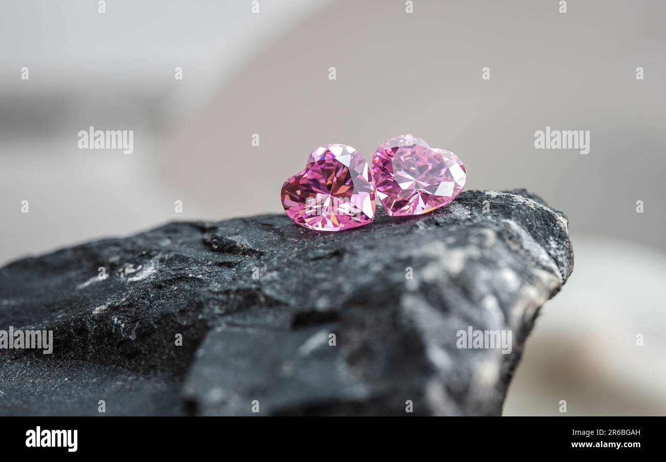 The glimmering natural heart shaped pink sapphire gemstones on a rugged ...