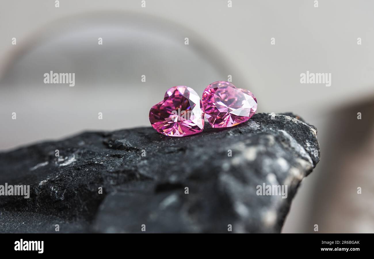 The glimmering natural heart shaped pink sapphire gemstones on a rugged ...