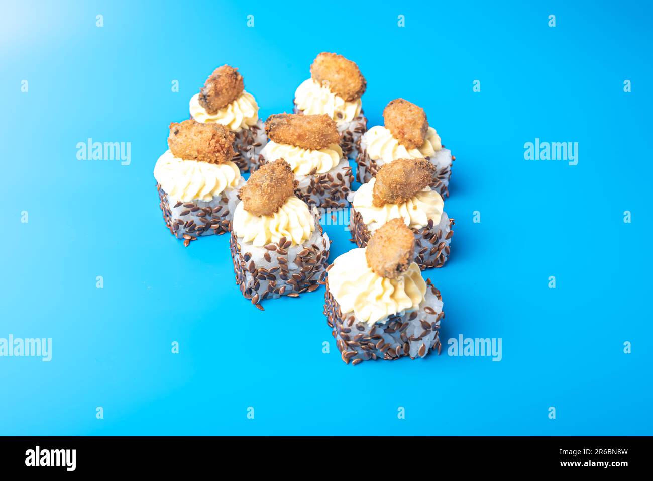 Sushi rolls with a mayonnaise cap and a mussel on top, sprinkled with ...