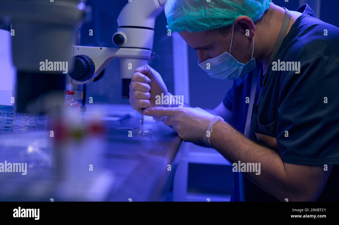 Laboratory worker examining fluid under microscope in clinic Stock ...